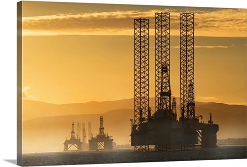 Oil drilling rigs out in the ocean with a view of the coastline ...