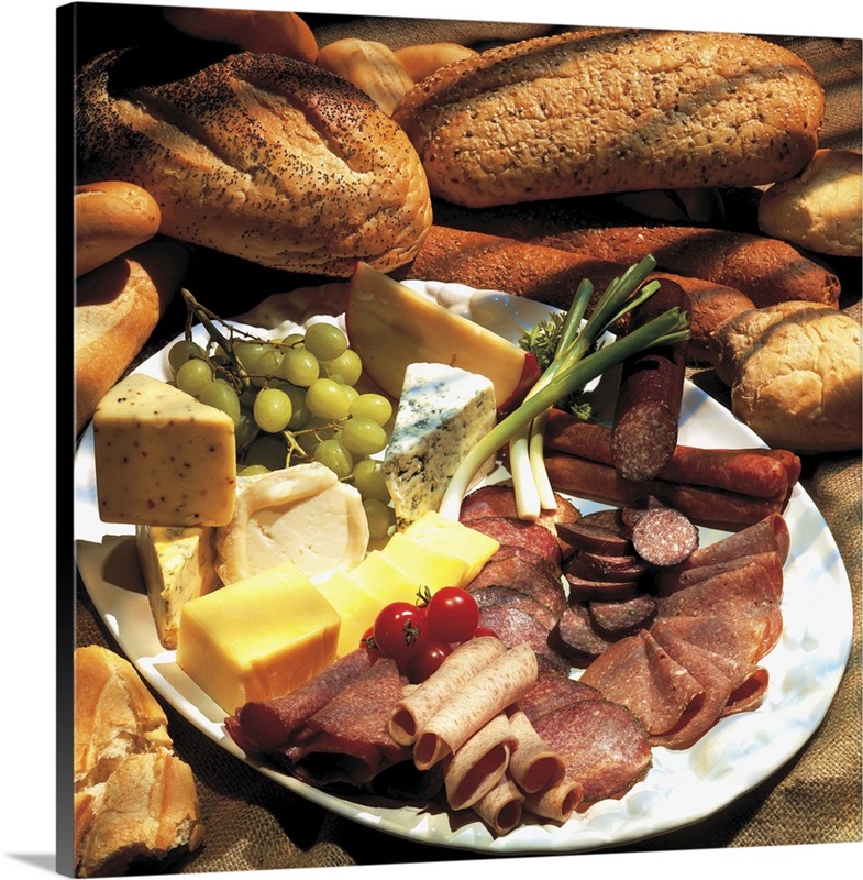 an array of assorted cold cuts and cheeses served with loaves of bread ...