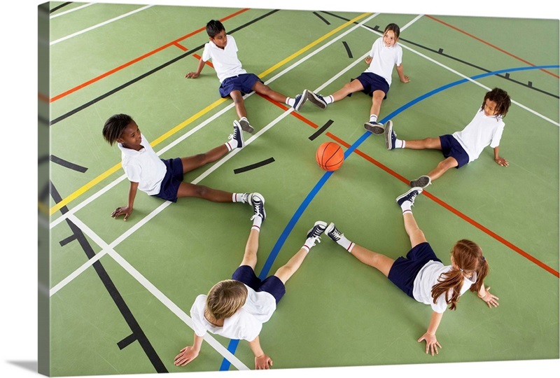 Children sitting on the floor of a sports hall with a basketball ...