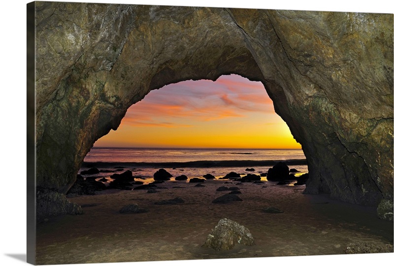 Dramatic sunset seen from inside cave on beach. | Great Big Canvas