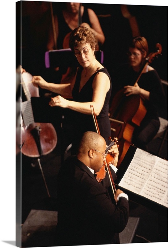 Female conductor and male violin soloist performing in orchestra ...