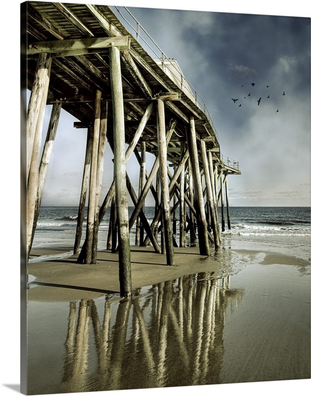 Fishing shack pier with reflection in sea and flock of birds in sky ...