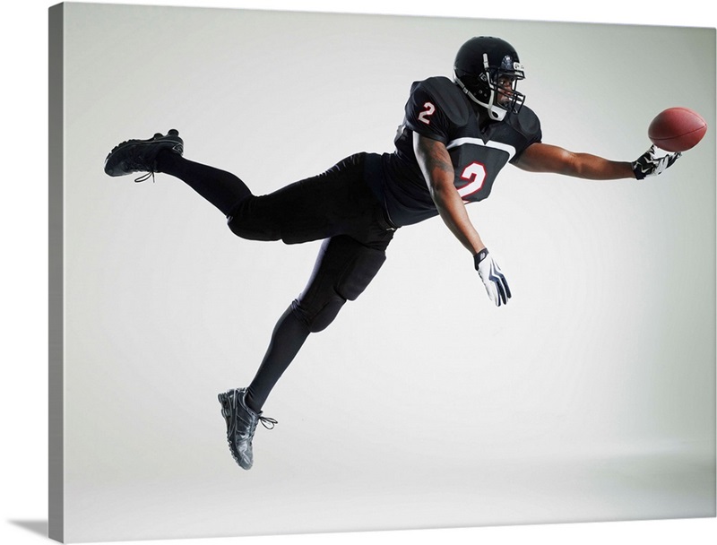 Football player leaping in mid air to catch ball | Great Big Canvas