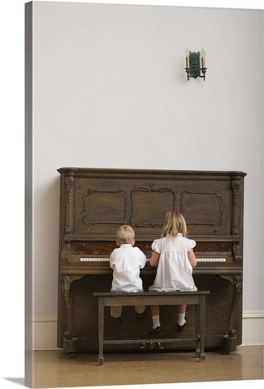 Girl and boy sitting on bench playing piano, rear view | Great Big Canvas