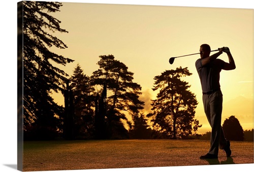 Golfer swinging club on golf course at sunset | Great Big Canvas