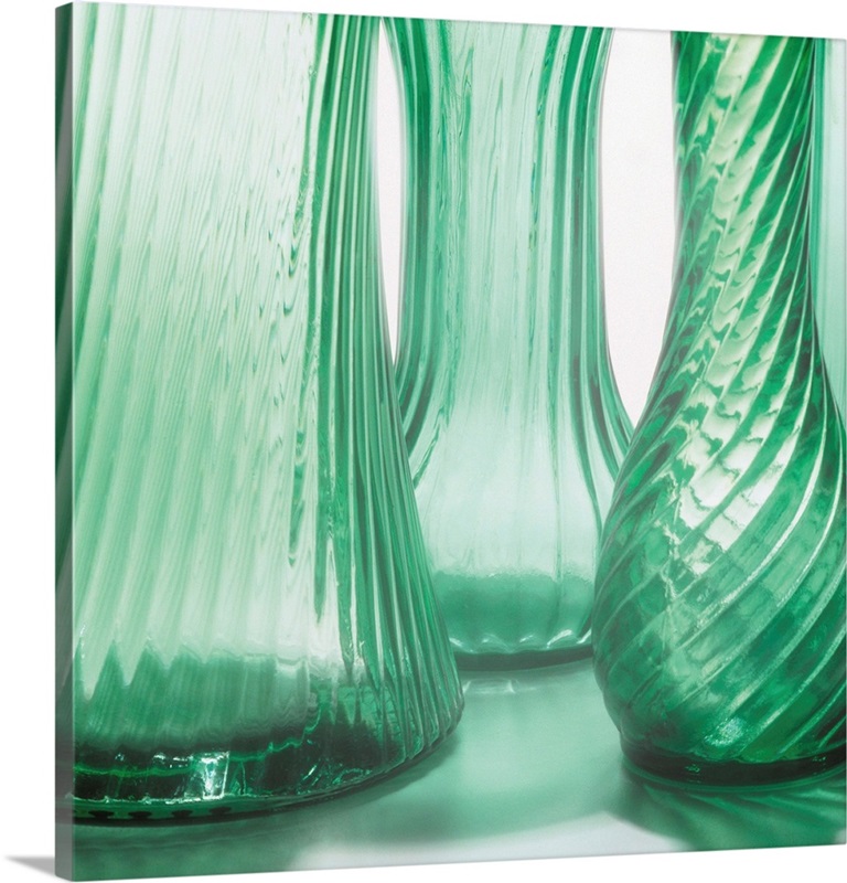 intricately designed glass vases stand together on a reflective surface ...