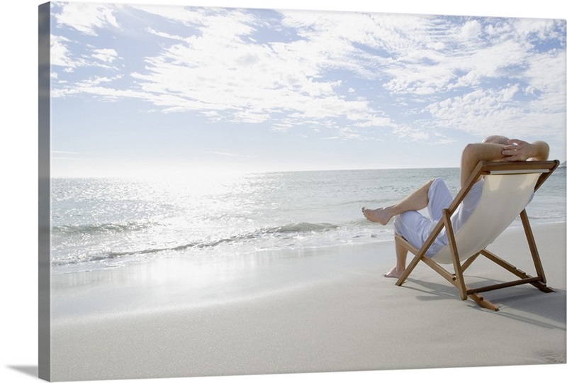 Man in lounge chair on beach | Great Big Canvas