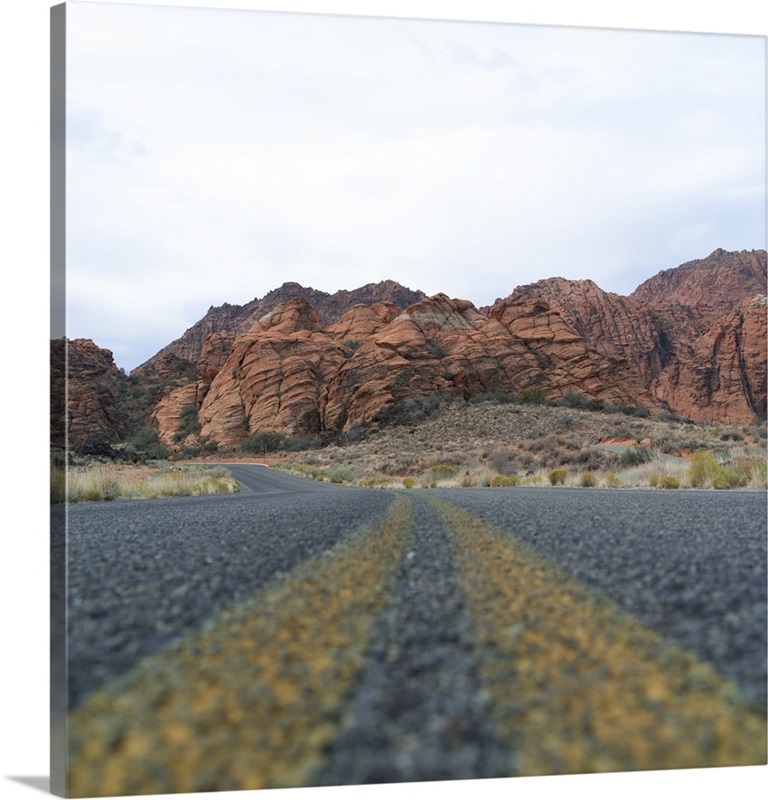 Portrait of a rural road with red rock mountains in the background ...