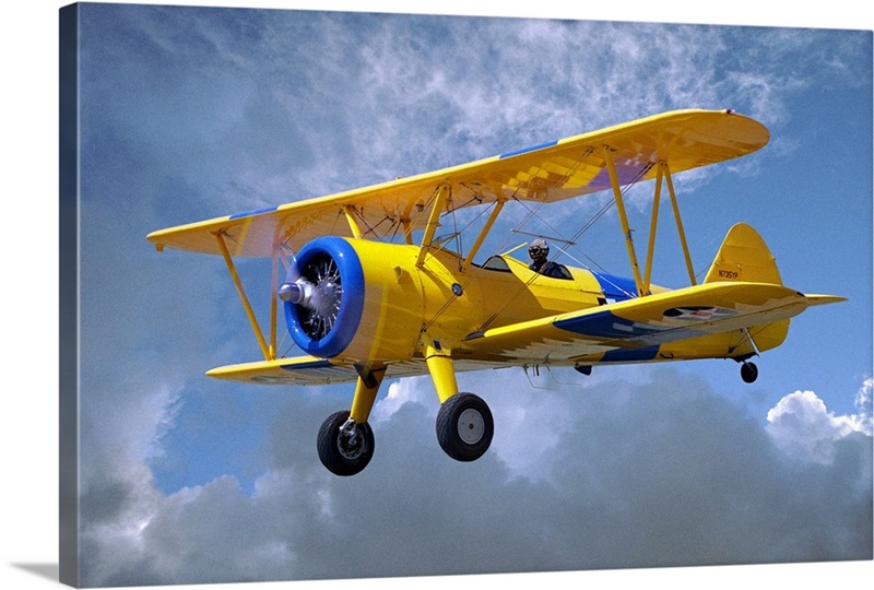 Yellow Stearman 5YP bi-plane flying in cloudy sky | Great Big Canvas