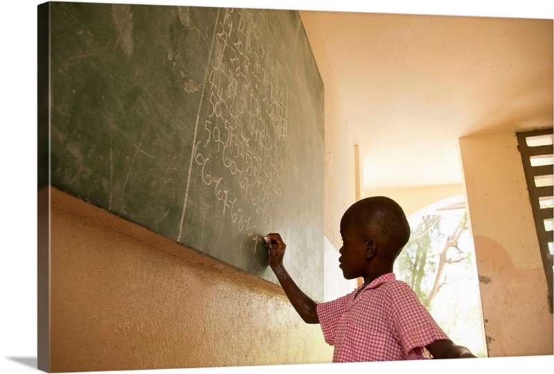Young boy in school writing on chalkboard | Great Big Canvas
