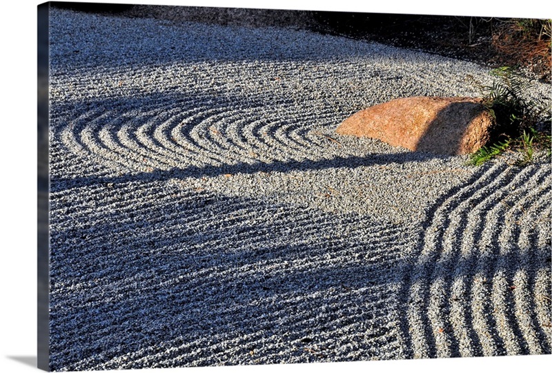 An embedded rock catches the afternoon sun in a raked rock garden ...