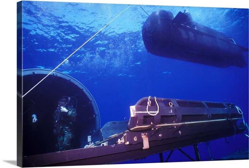A SEAL Delivery Vehicle hovers above the Dry Deck Shelter next to the ...
