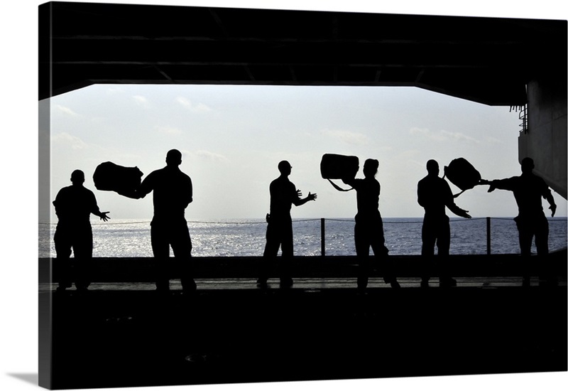 Sailors pass supplies to each other in the hangar bay of USS Ronald ...
