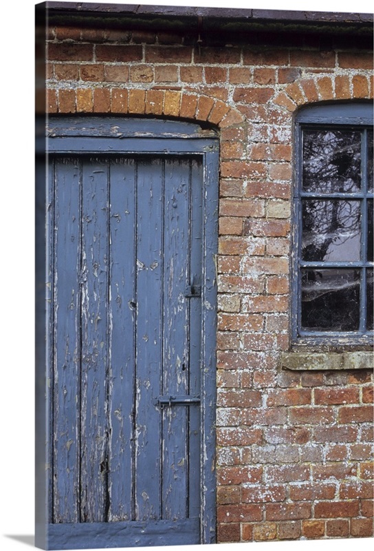 Old orange brick stable block with blue painted wooden door and windows ...