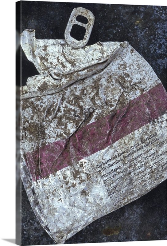 Squashed and split aluminium can with covering of dirt lying on metal ...