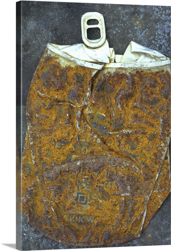 Squashed and split aluminium can with rusty sides lying on tarnished ...